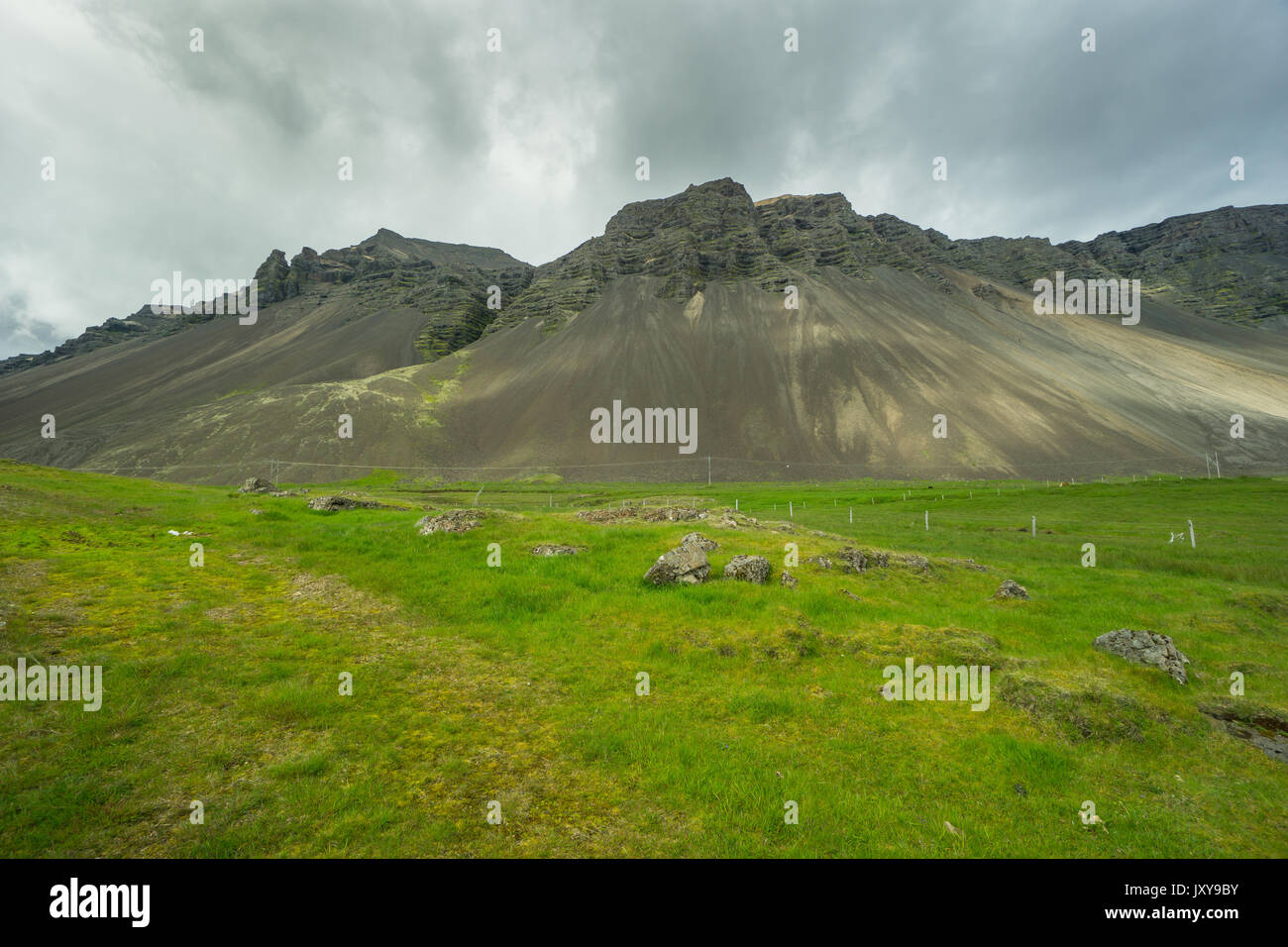 Iceland - Moss covered green volcanoe behind meadow with clouds Stock ...