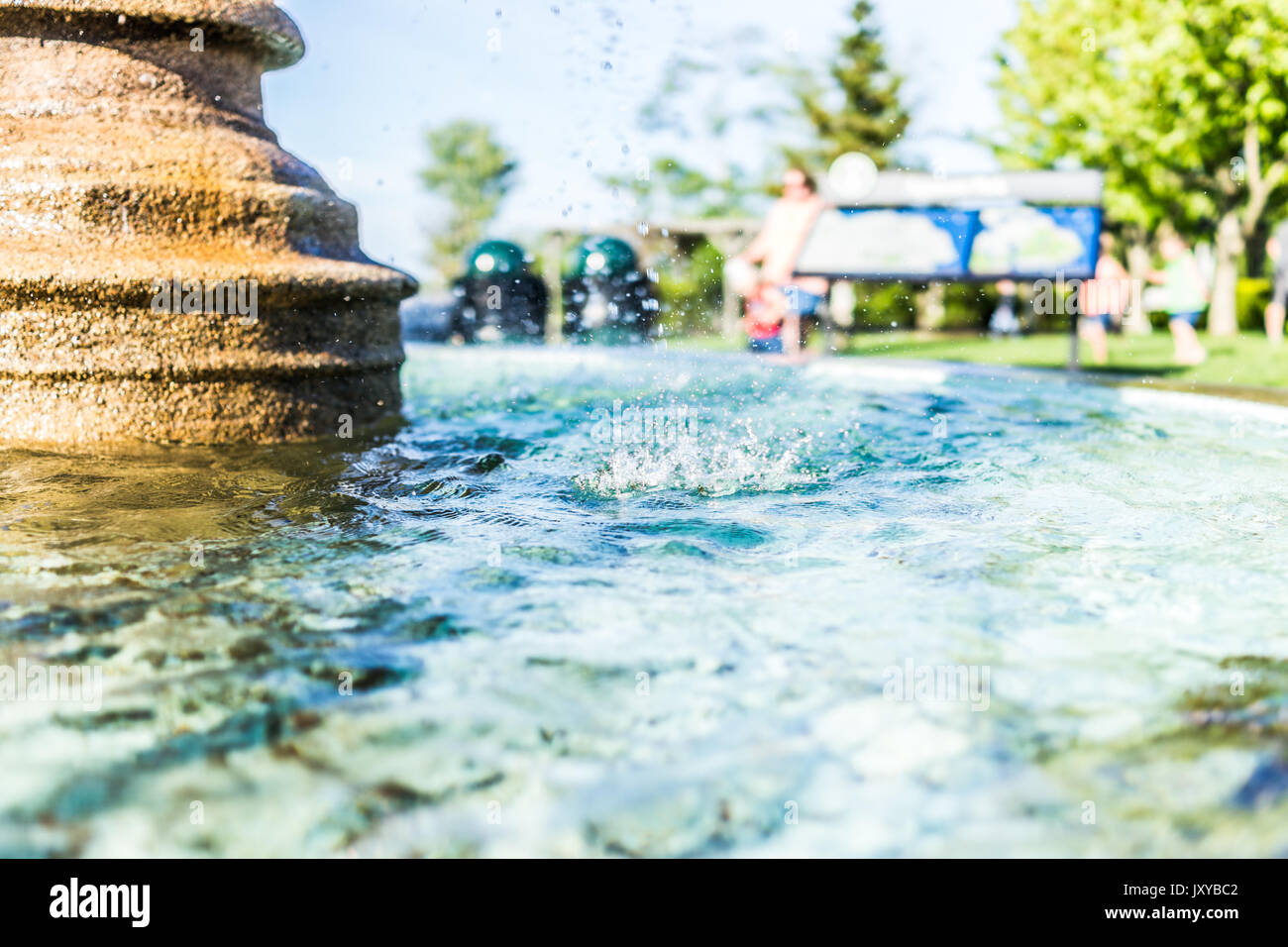 Closeup of splashing water fountain in downtown village park in summer ...