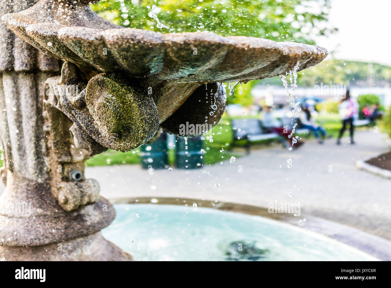 Closeup of splashing water fountain in downtown village park in summer ...