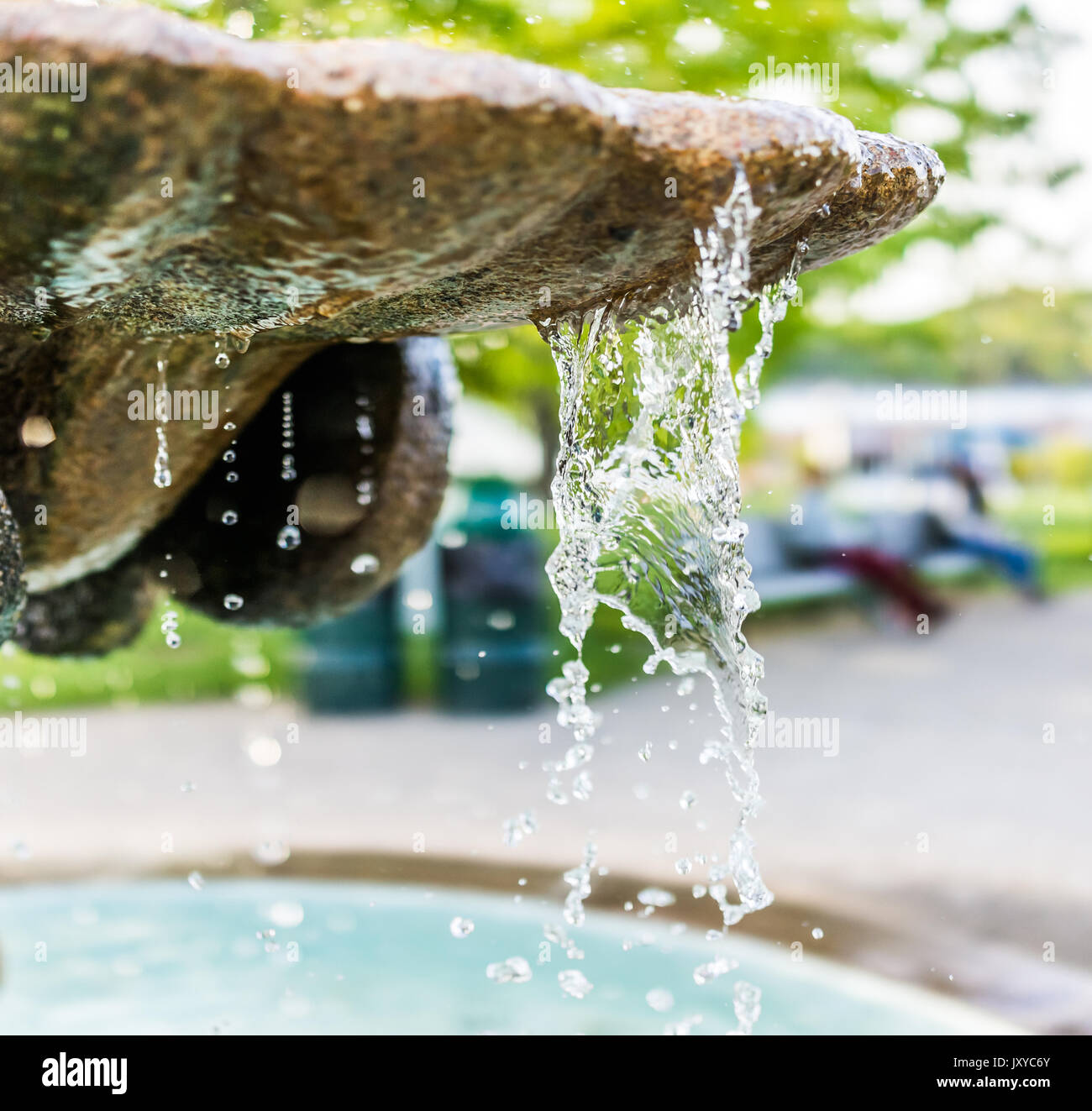Closeup of splashing water fountain in downtown village park in summer ...