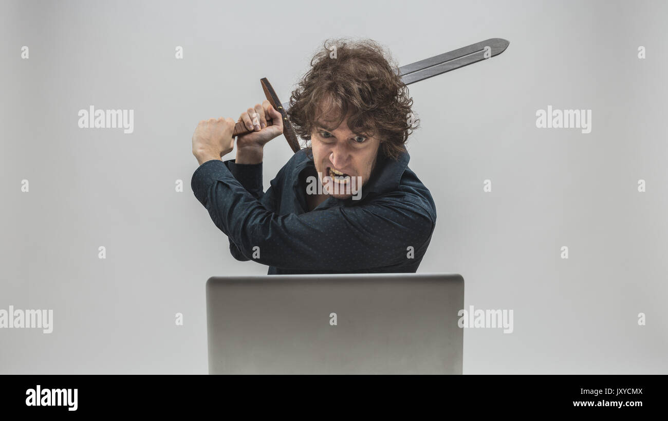 angry man about to destroy his laptop computer by hitting it with a ...