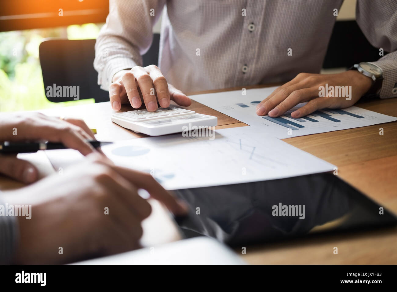 Two young businessmen using touchpad explaining his business plans to ...