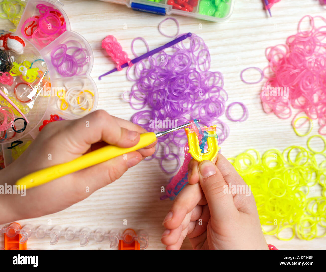 handwork, weaving rubber, colored elastics on the table. Hands girls ...