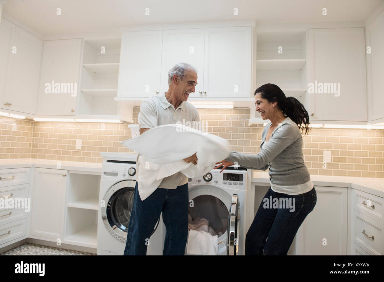 Playful couple folding towel in modern laundry room Stock Photo - Alamy