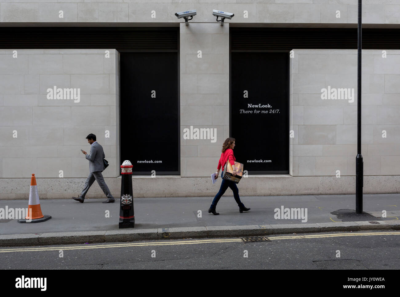 Londoners walk beneath two CCTV cameras in the City of London, one of ...