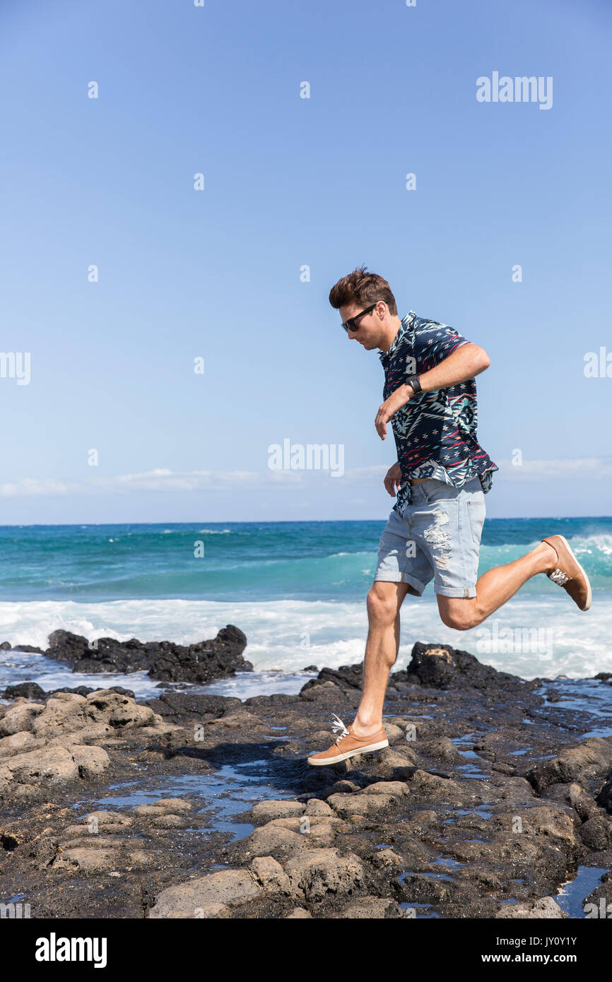 Caucasian man running on rocks on beach Stock Photo - Alamy