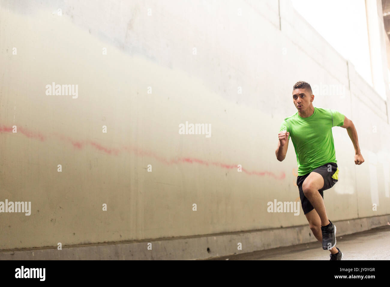 Mixed Race man running near wall Stock Photo - Alamy