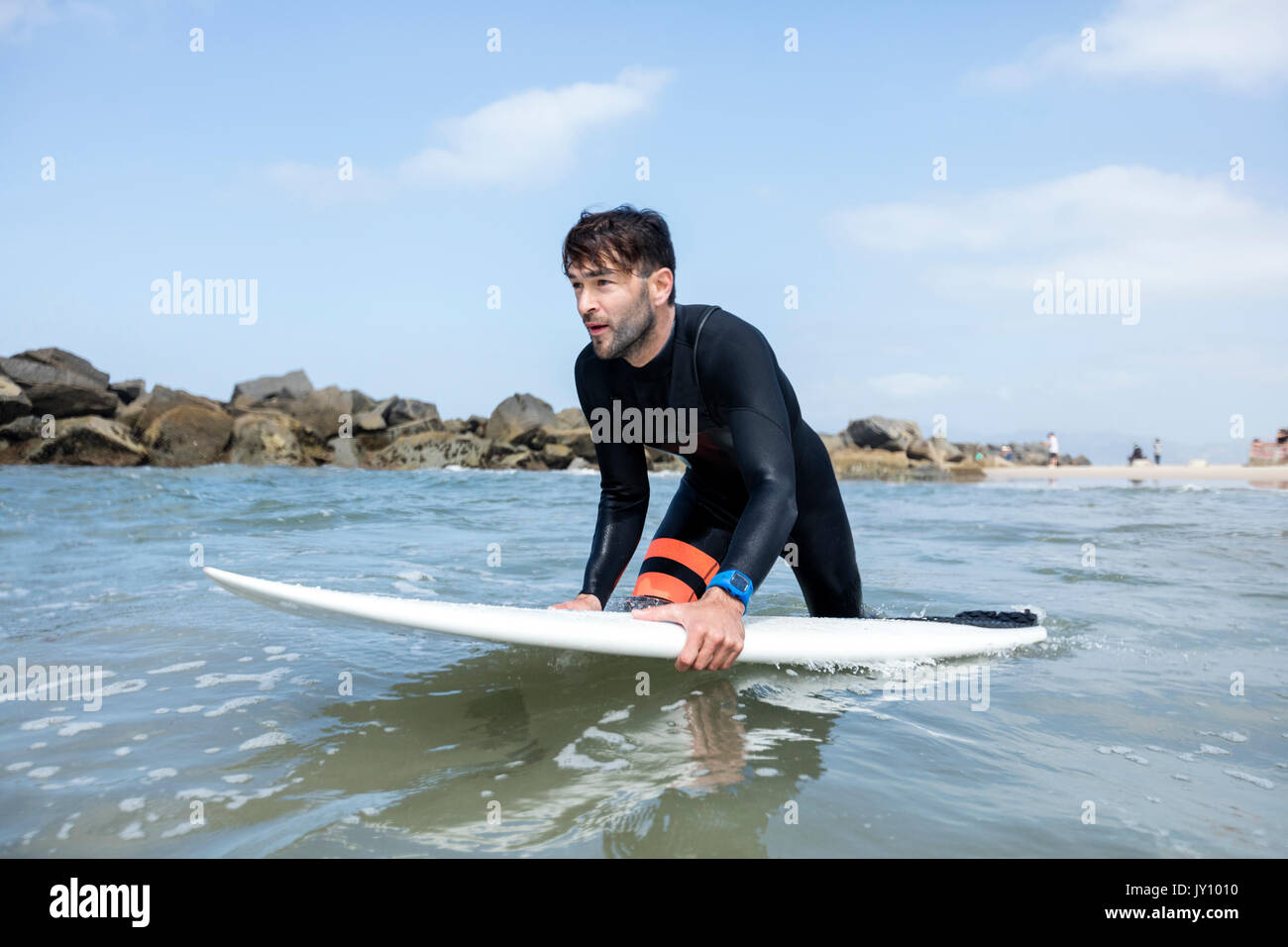 Caucasian man wading in ocean holding surfboard Stock Photo - Alamy