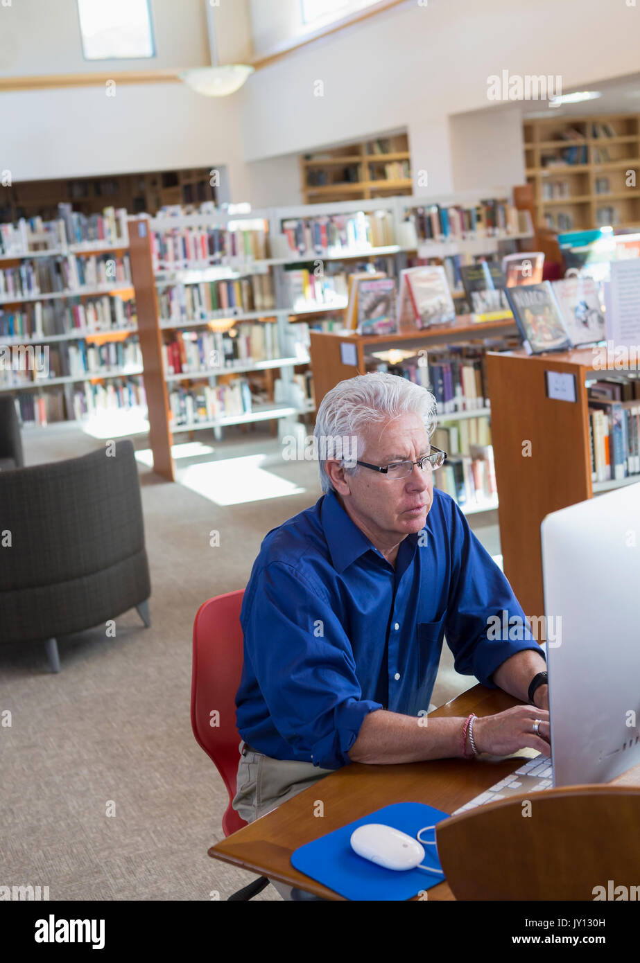 Serious Hispanic man using computer in library Stock Photo - Alamy
