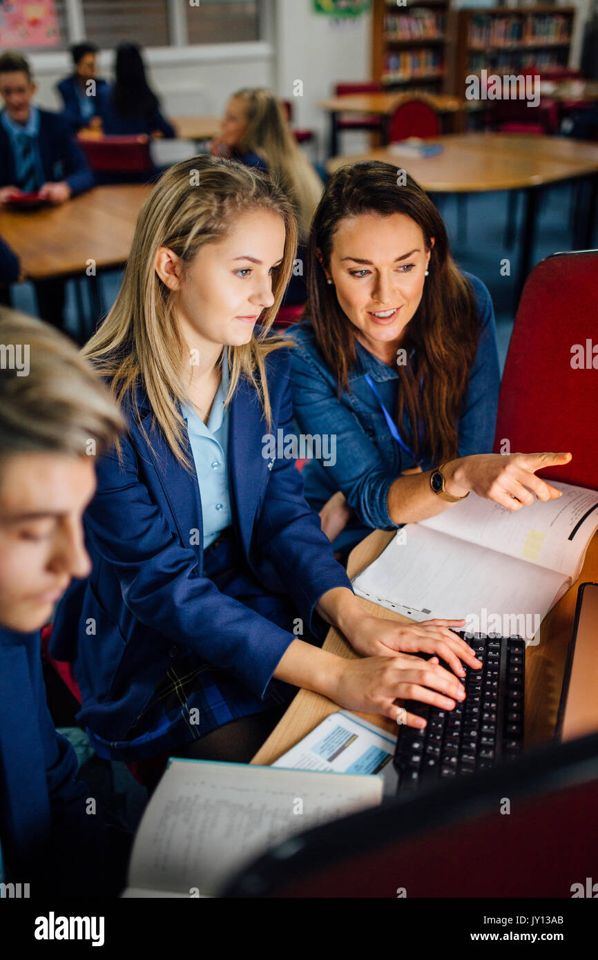 Teen student is working with her teacher on the computer during her ...