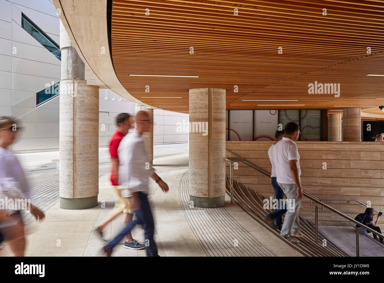 People move across the frame and descend the staircase and columns of ...