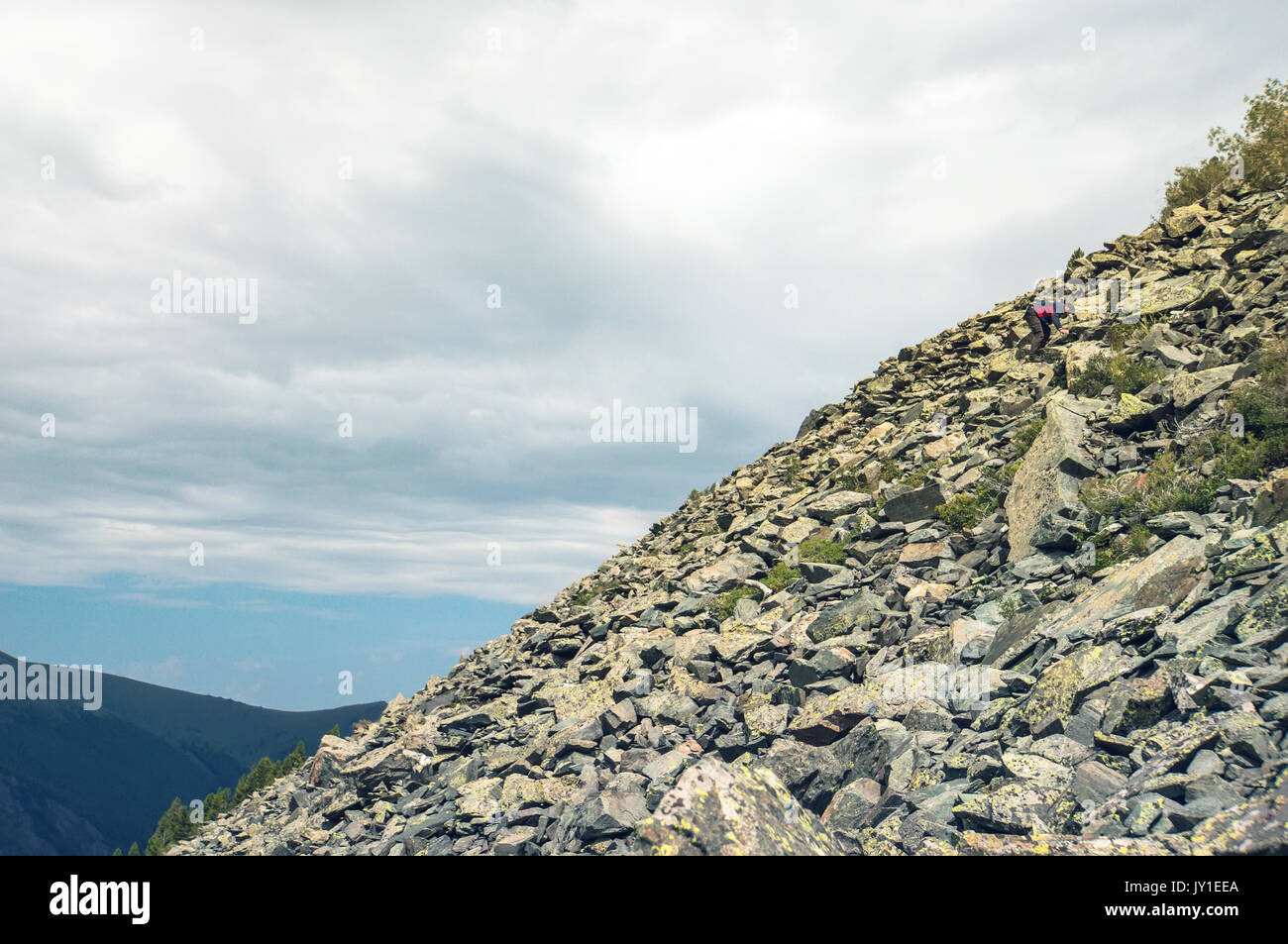 a tourist makes its way through the stone placers Man climb on mountain ...