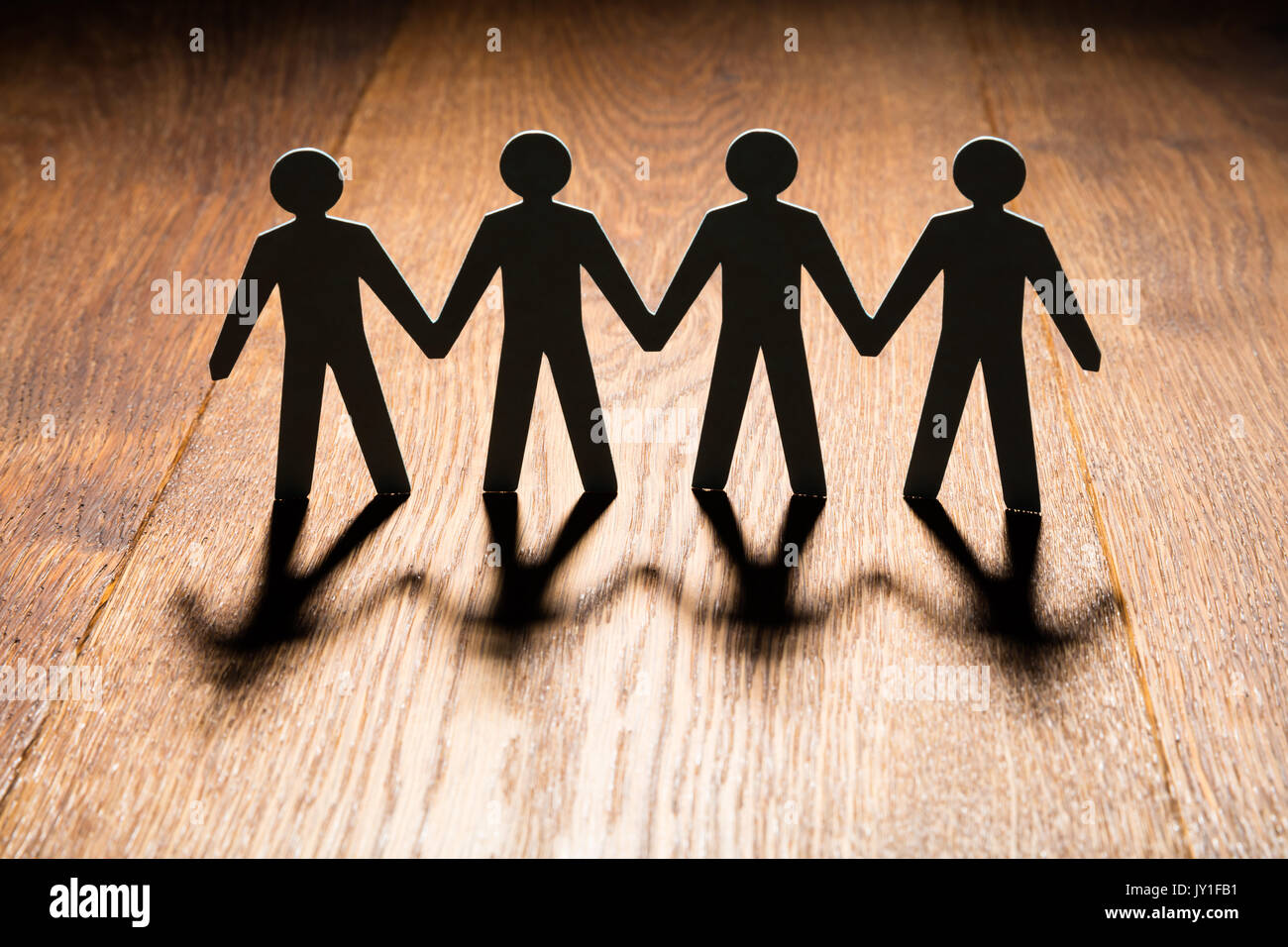 Silhouette Of Papercut People On Wooden Desk Stock Photo - Alamy