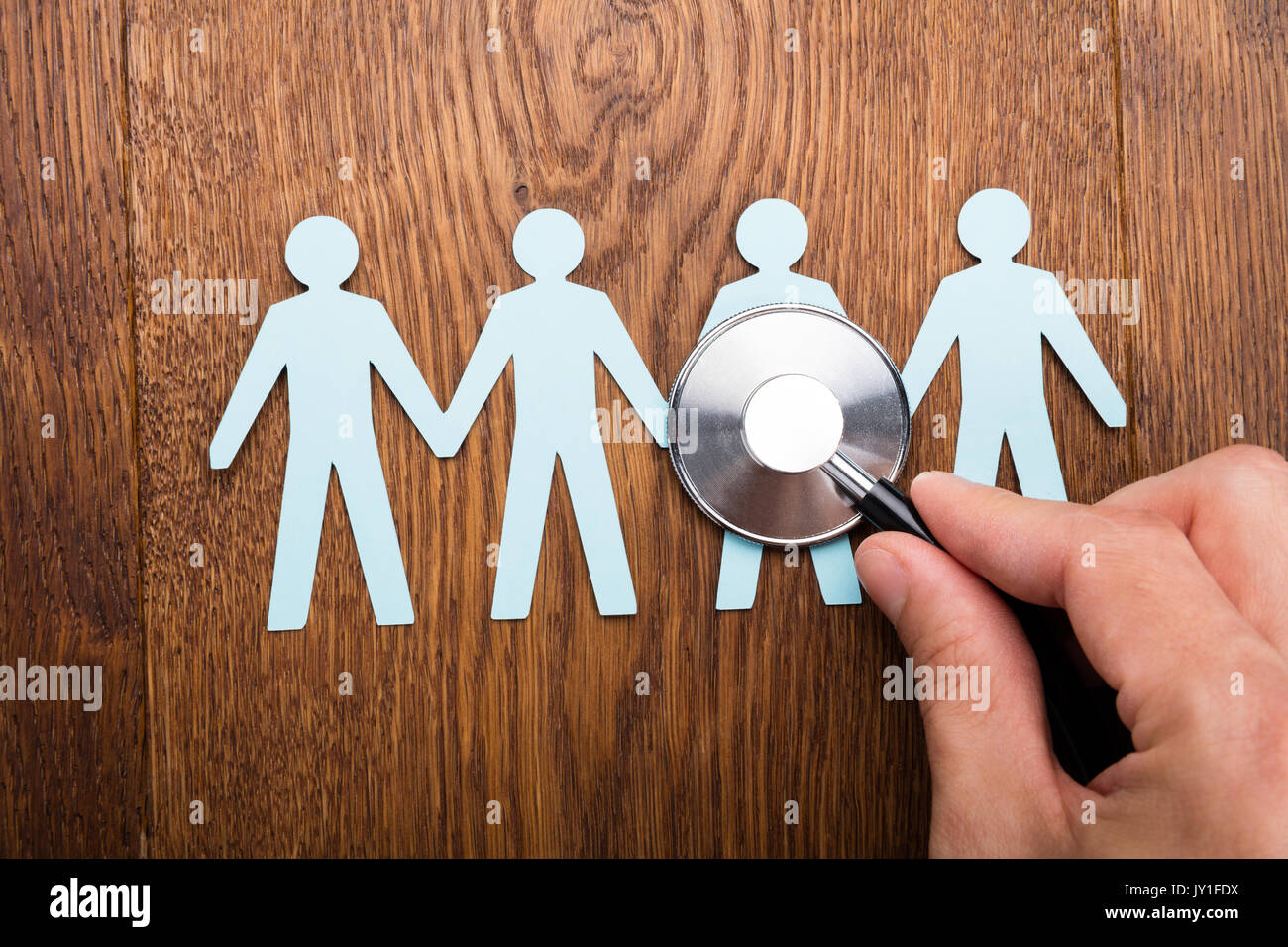 Person Using Stethoscope On Papercut With People Chain On Wooden Desk ...