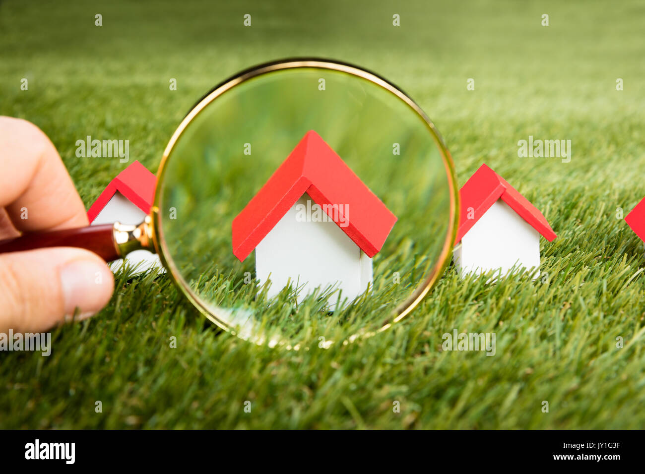Person Hands With Magnifying Glass Inspecting A Model House On Grassy ...
