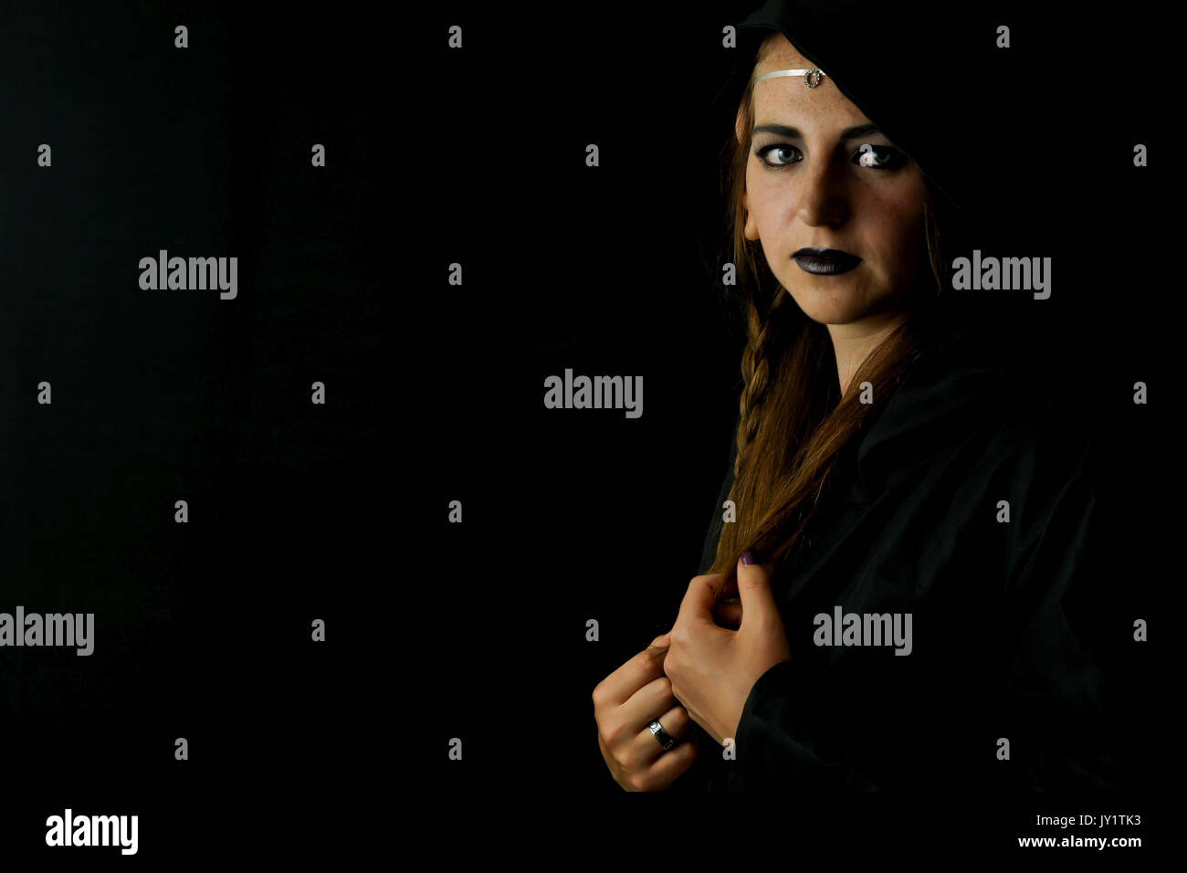 A young woman dressed as an elf with a black hooded robe and long hair ...