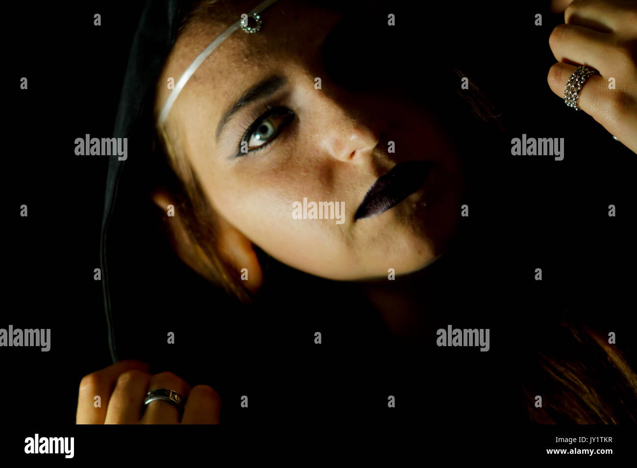 A young woman dressed as an elf with a black hooded robe and long hair ...