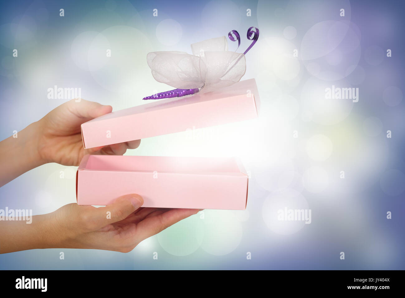 The hand is opening the gift box with magical special effects lights ...
