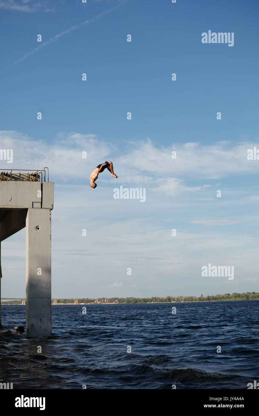 A man is jumping into the sea from a high pier. Adrenaline and extreme ...