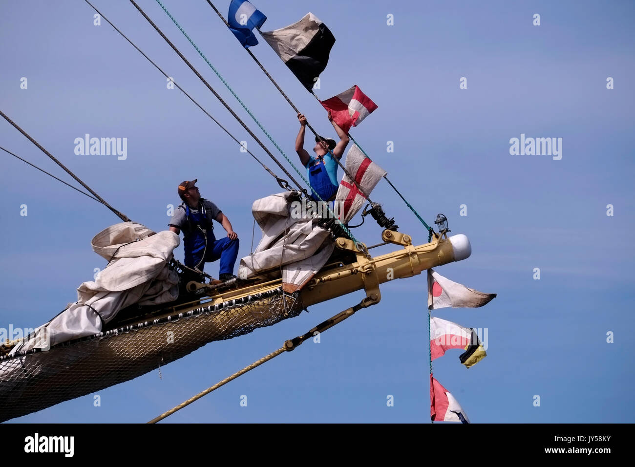 Men hanging different national flags in forestay over a bowsprit of a ...