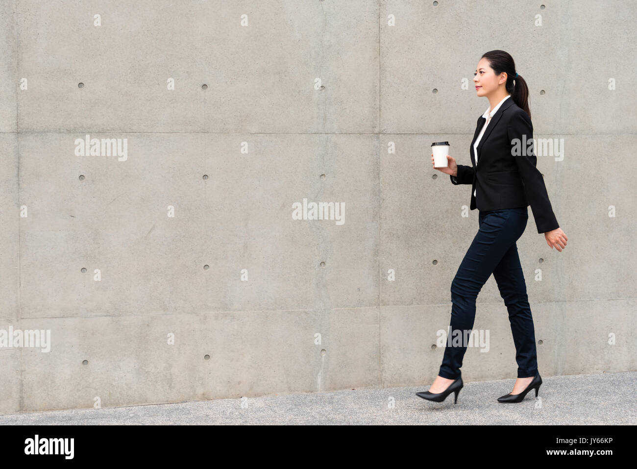 elegant manager rights woman walking on gray wall building outdoor ...