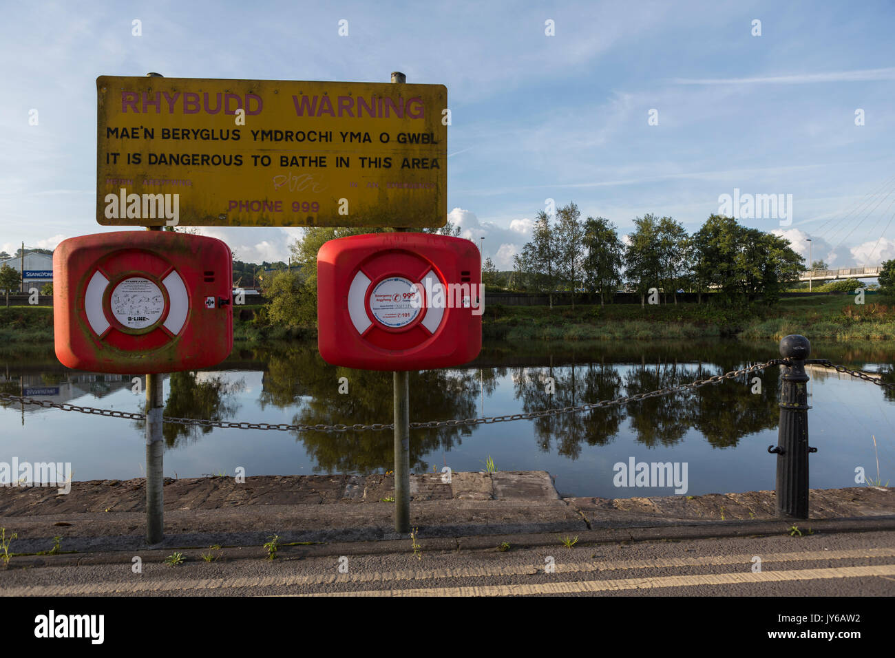 Sign warning not to swim in river, with flotation aids, by riverside ...