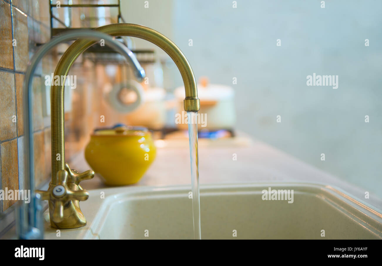 modern, trendy, bronze faucet in a new modern kitchen. From the tap is ...