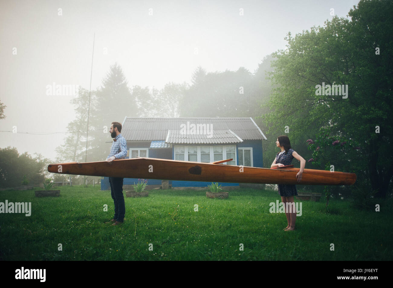 romantic couple in love holding wooden canoe while standing in ...