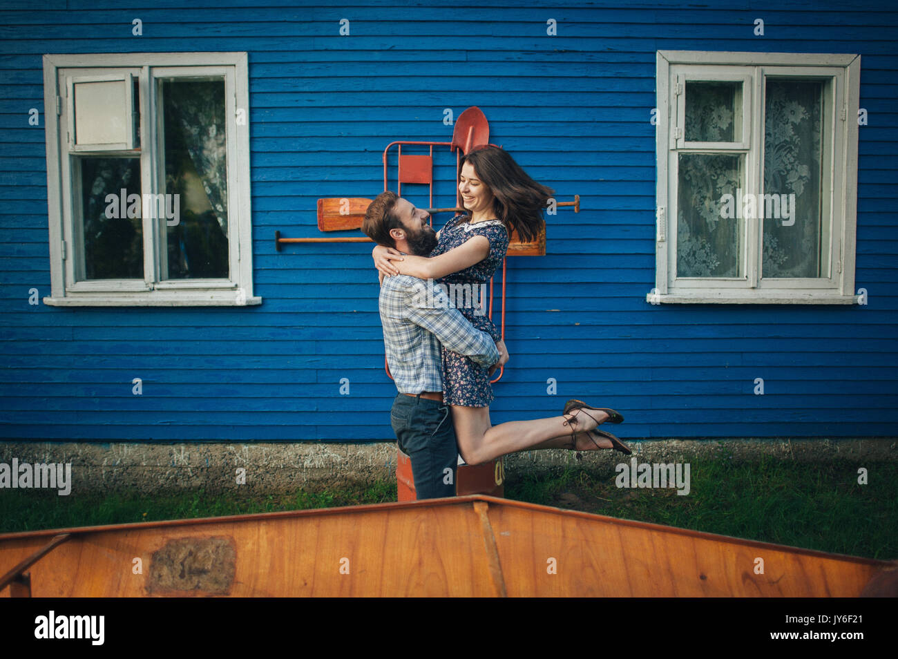 happy couple in love enjoying while standing near canoe and blue house ...