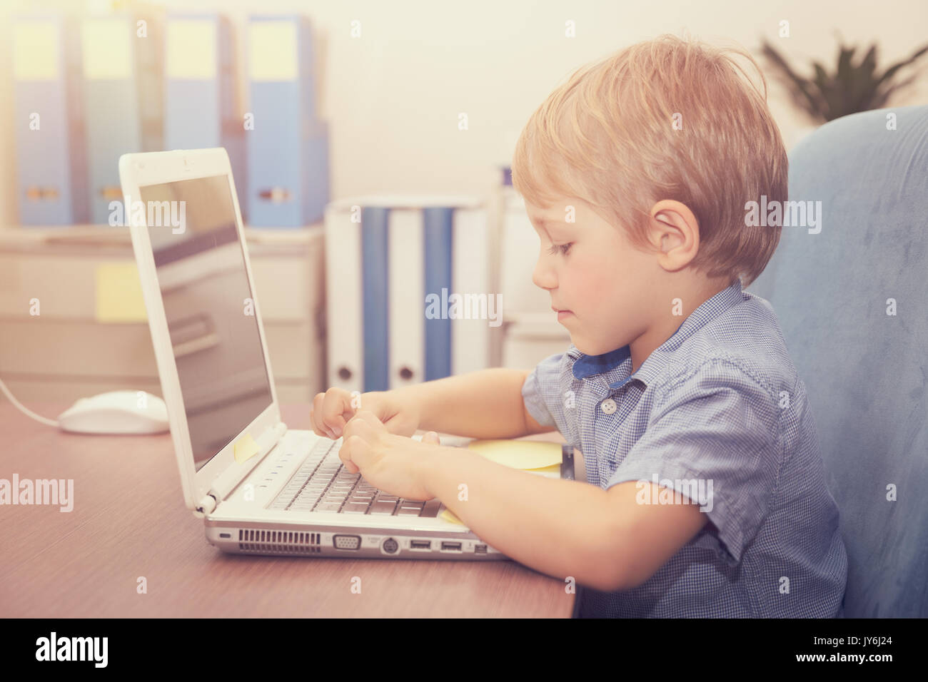 Little boy working on the laptop at home, cute schoolboy doing homework ...