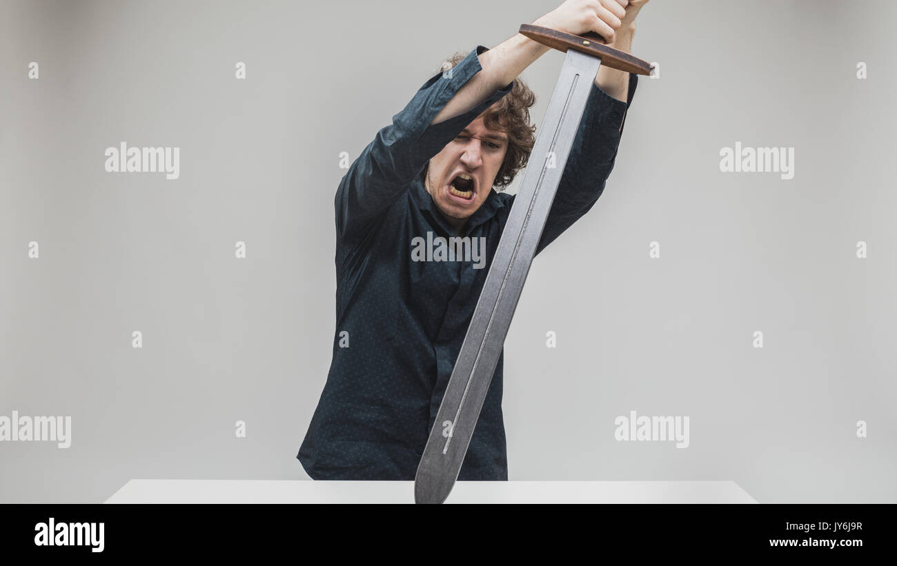 angry man hitting his desk with a sword - concept of rage problems ...