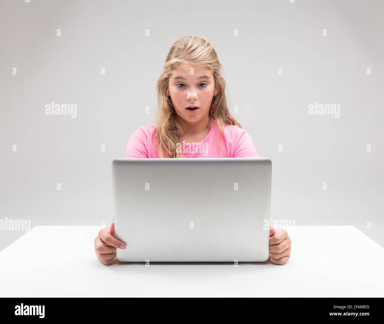 little girl shocked by something happening on her laptop computer ...