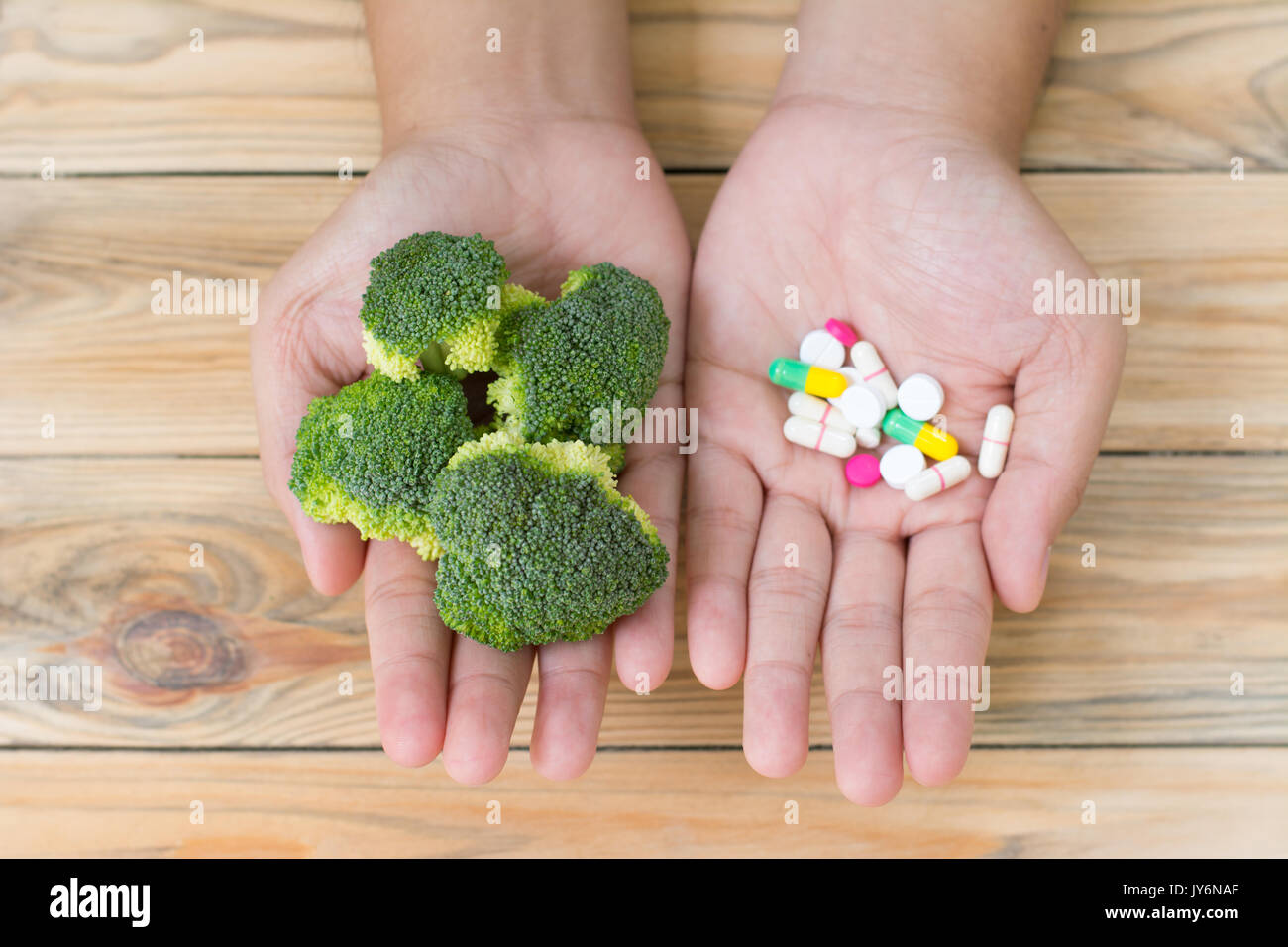 broccoli and drugs in hands. a wooden background. healthy eating ...