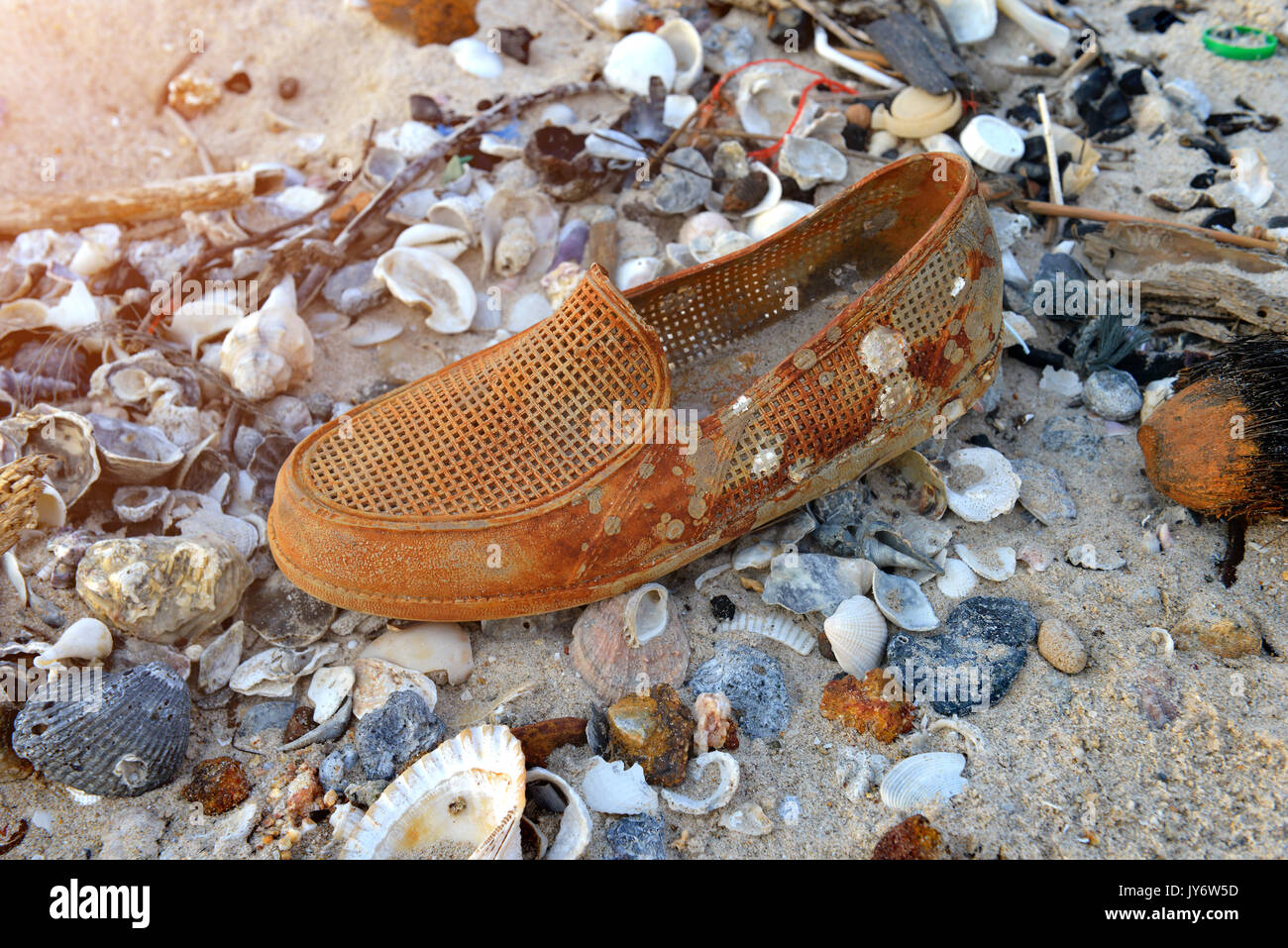 One old and dirty rubber shoe on the beach garbage whith the shells on ...