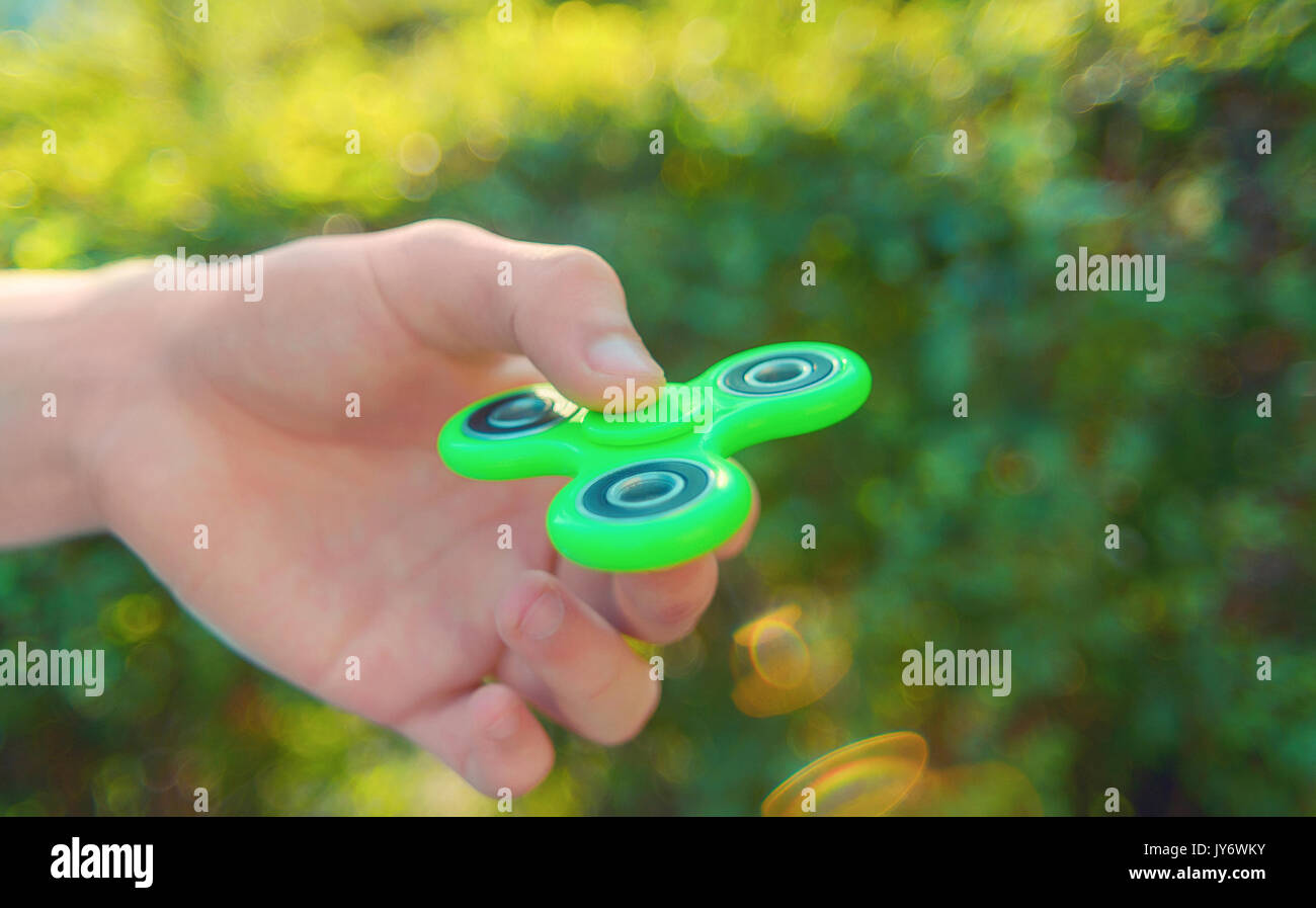 Young man hand holding popular antistress gadget fidget spinner. Man ...