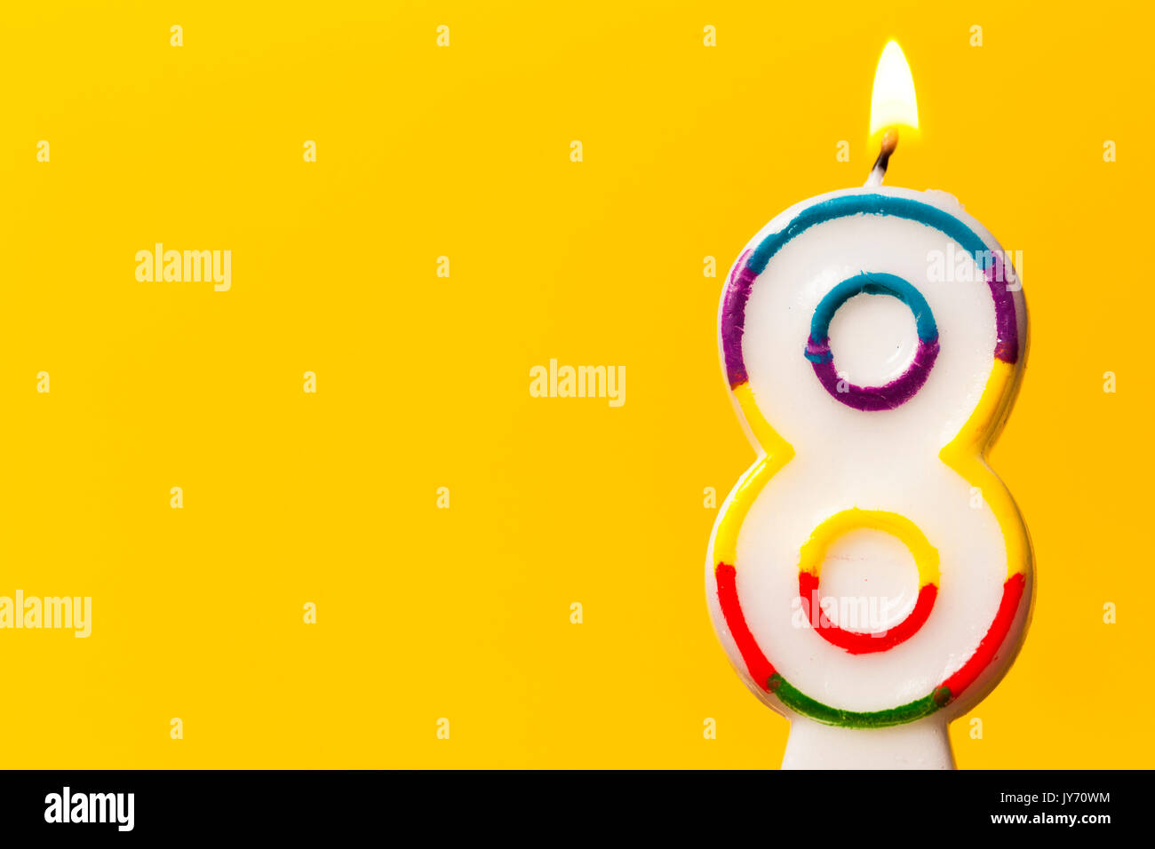 Number 8 birthday celebration candle against a bright yellow background ...