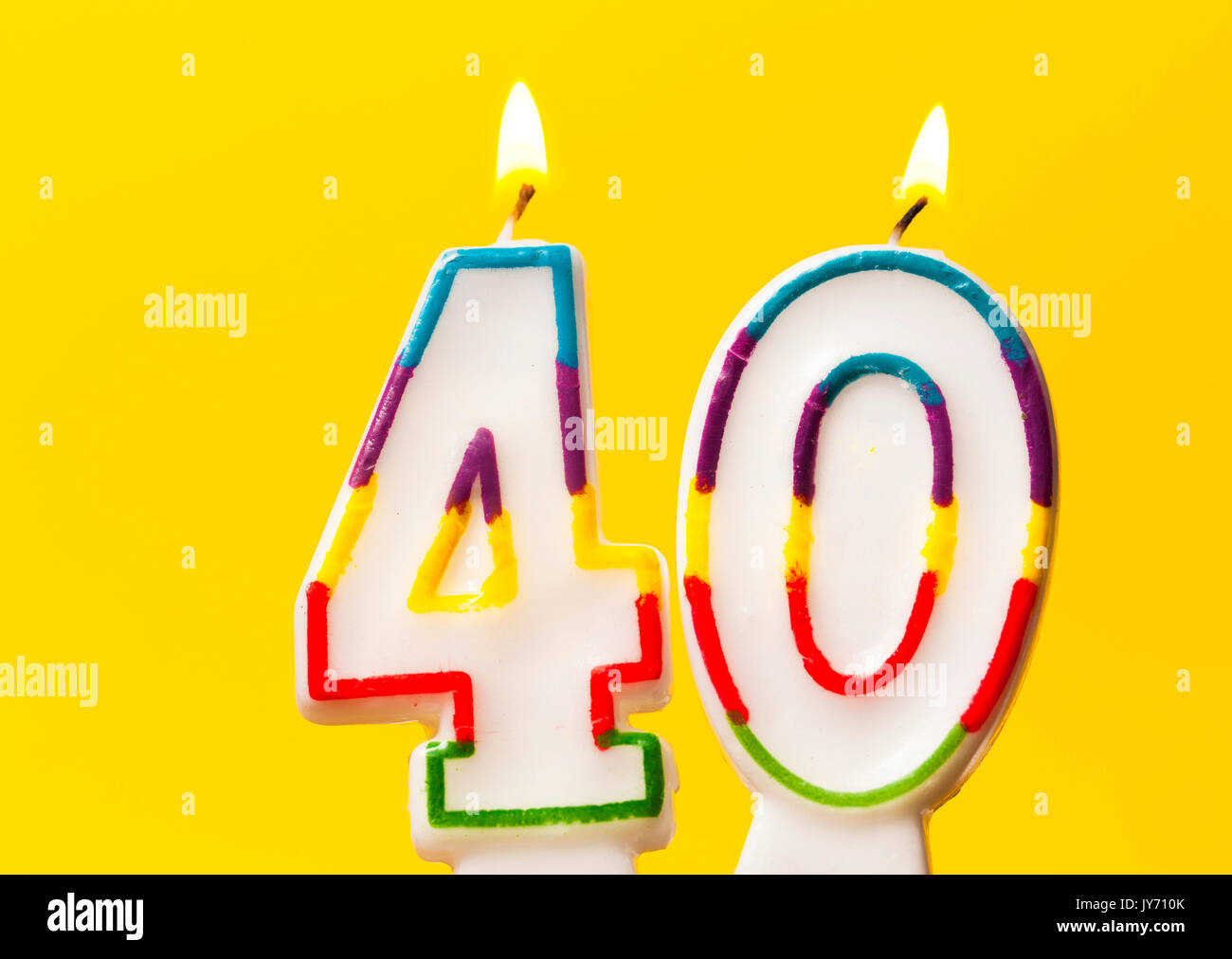 Number 40 birthday celebration candle against a bright yellow ...