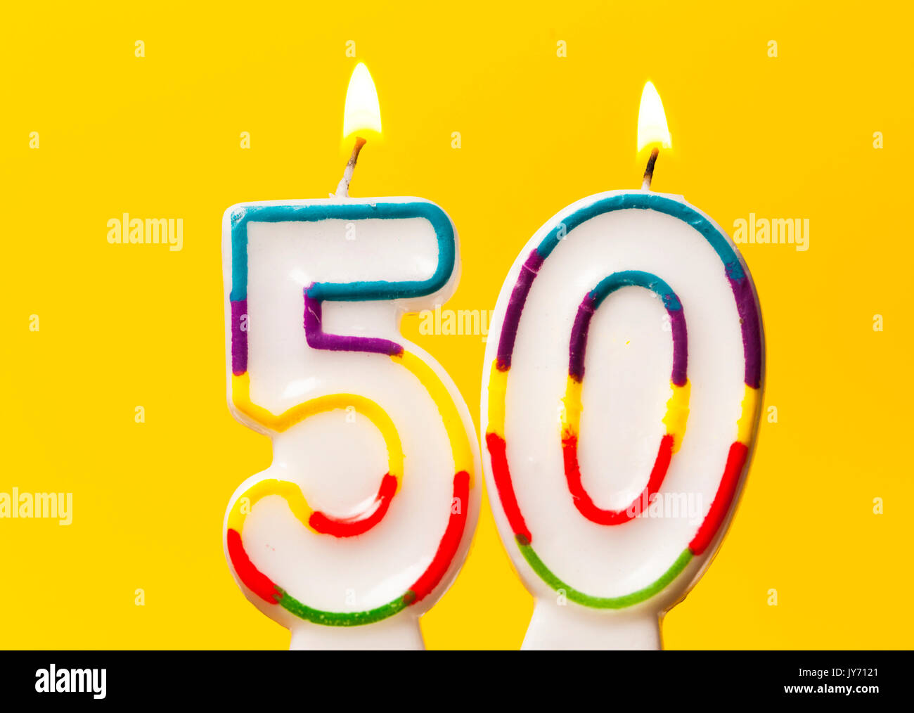 Number 50 birthday celebration candle against a bright yellow ...