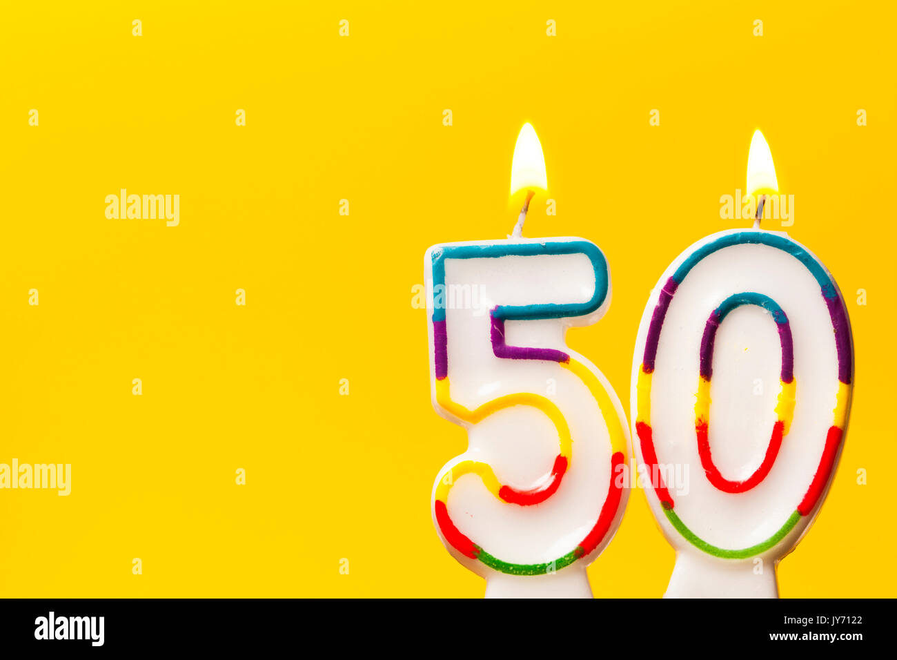 Number 50 birthday celebration candle against a bright yellow ...