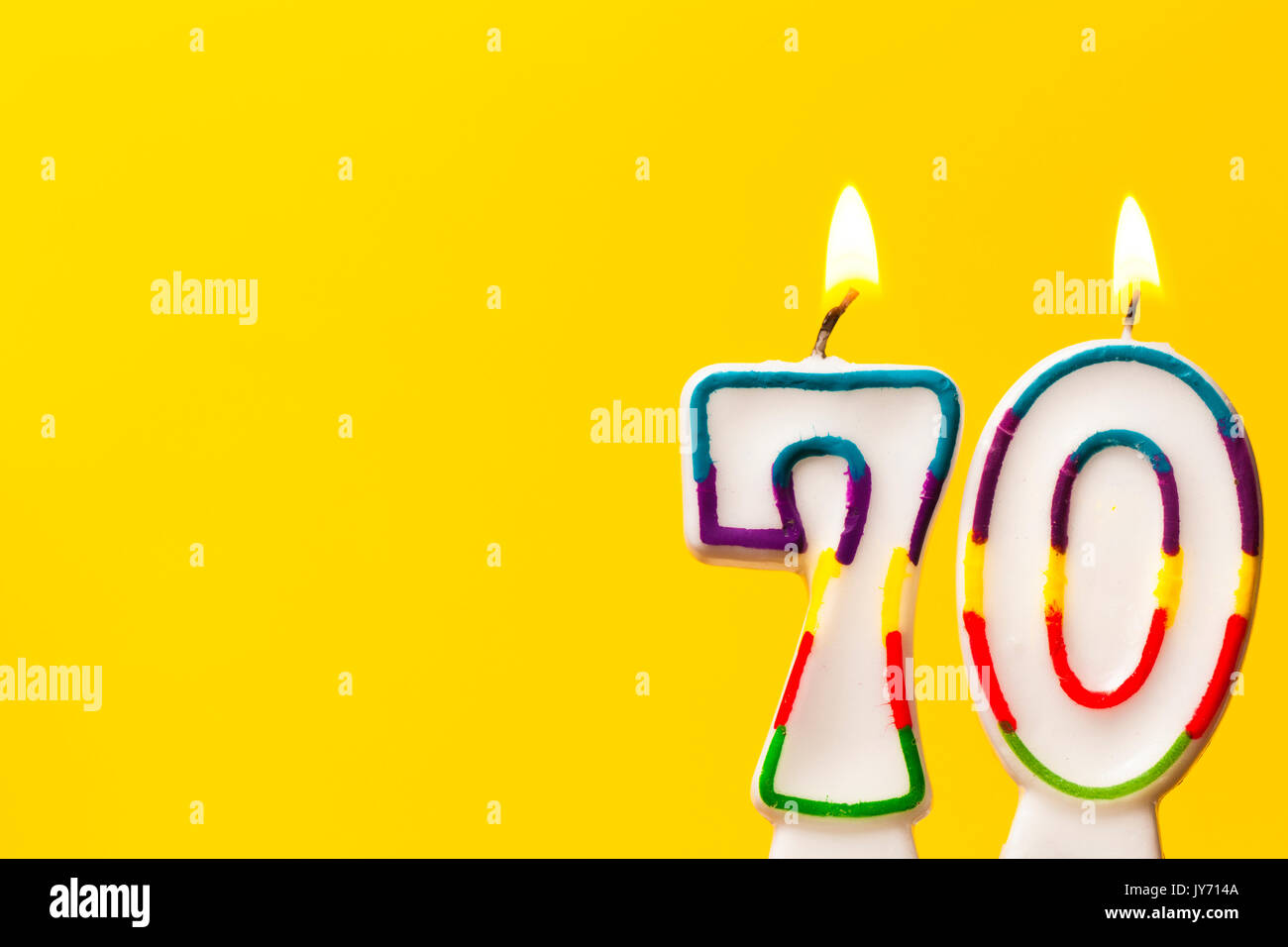Number 70 birthday celebration candle against a bright yellow ...