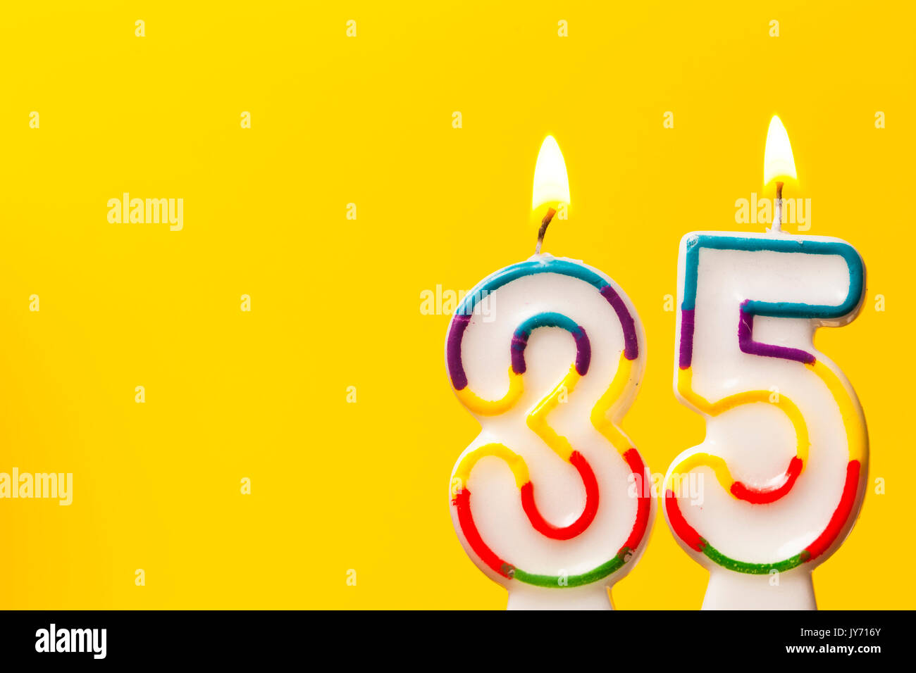 Number 35 birthday celebration candle against a bright yellow ...