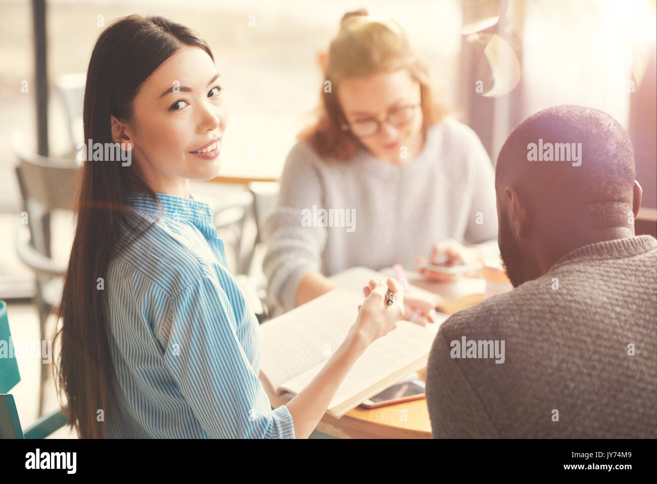 Pleasant young woman studying with her groupmates Stock Photo - Alamy