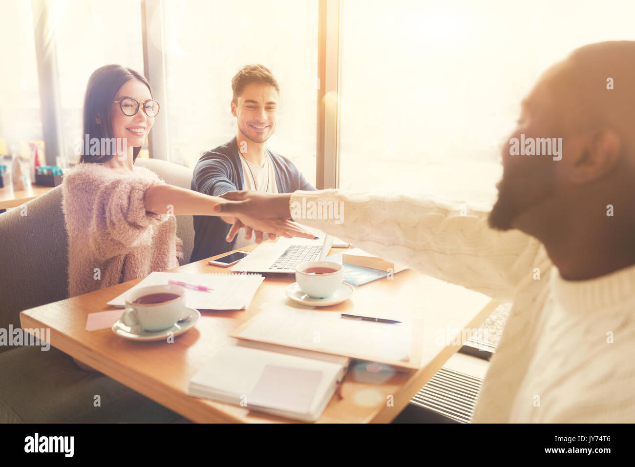 Positive friendly international students holding hands together Stock ...