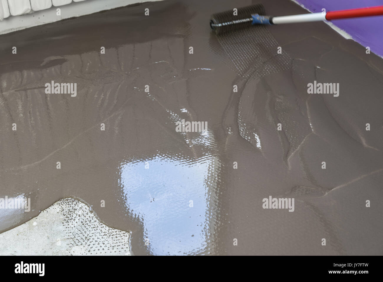 Interior of house under construction. Spreading self leveling plaster ...