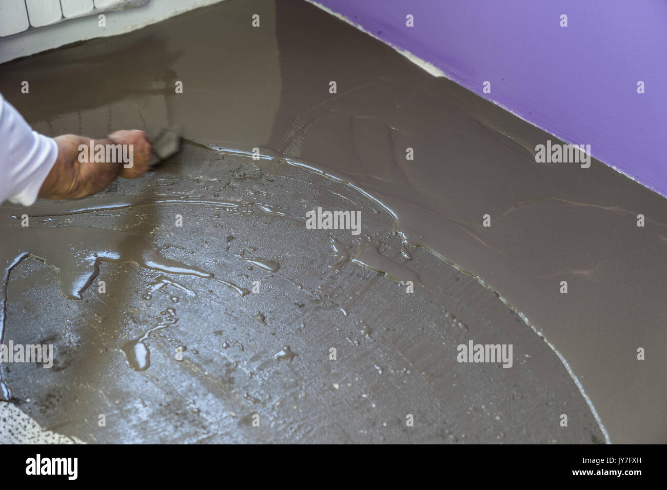 Apartment under construction. Worker puts a self leveling screed on ...