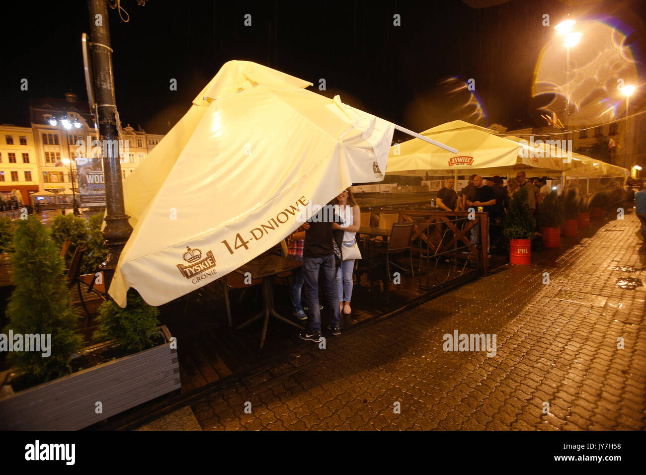 People are seen taking over under a damaged parasol after a heavy storm ...