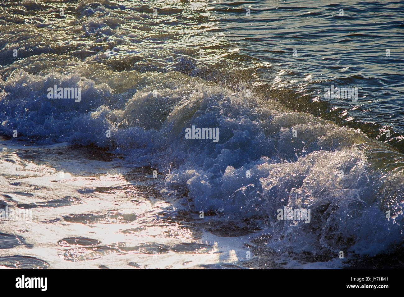 Sea rolling and receding water in rays of setting sun. Black sea ...