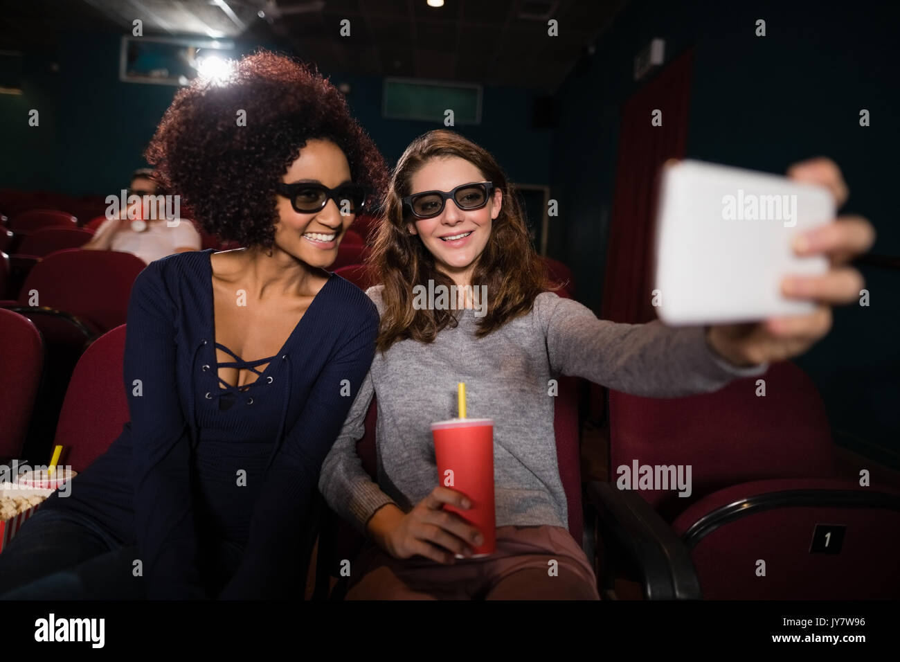 Friends taking a selfie while watching movie in theatre Stock Photo - Alamy