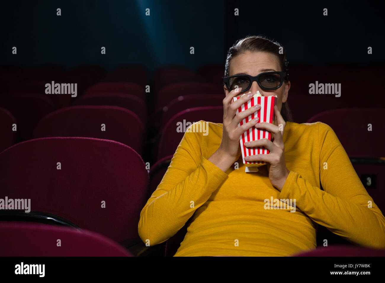 Woman scared while watching movie in theatre Stock Photo - Alamy