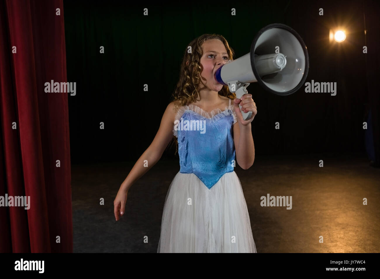 Female artist announcing on megaphone on stage in theatre Stock Photo ...